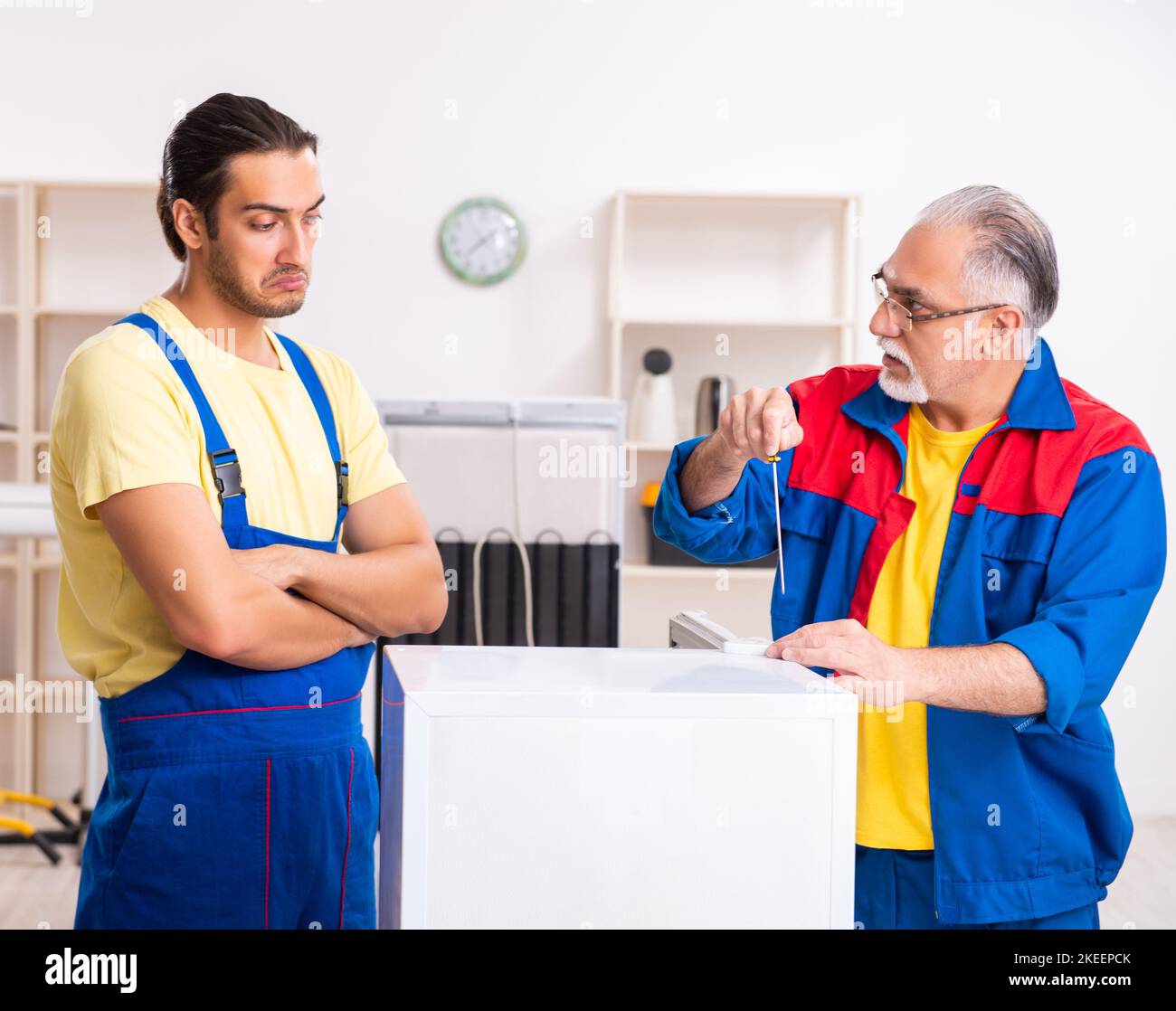 The two contractors repairing fridge at workshop Stock Photo - Alamy