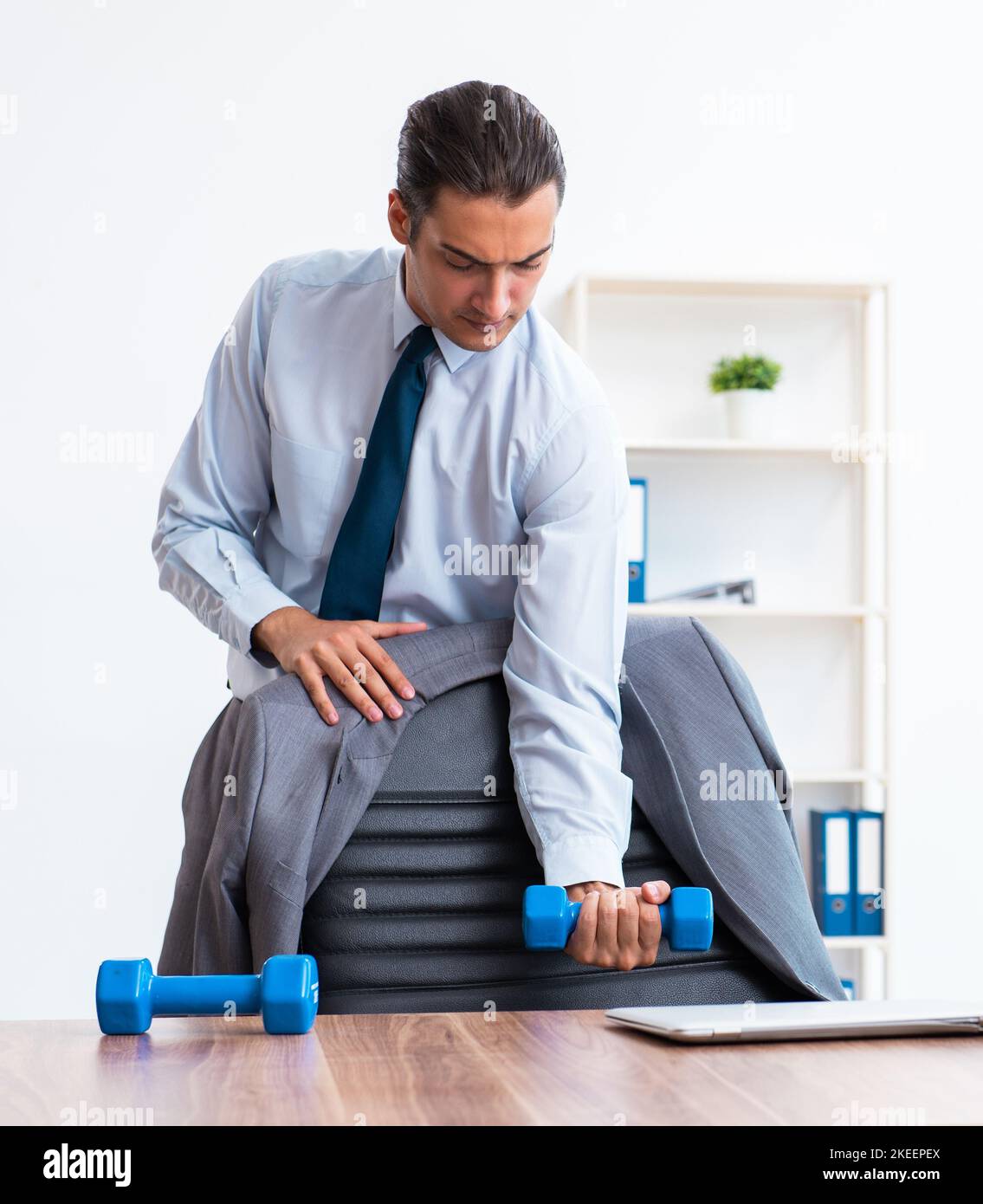 The young handsome employee doing sport exercises at workplace Stock ...
