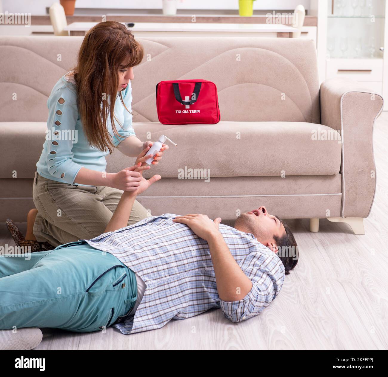 The young couple in first aid concept at home Stock Photo - Alamy