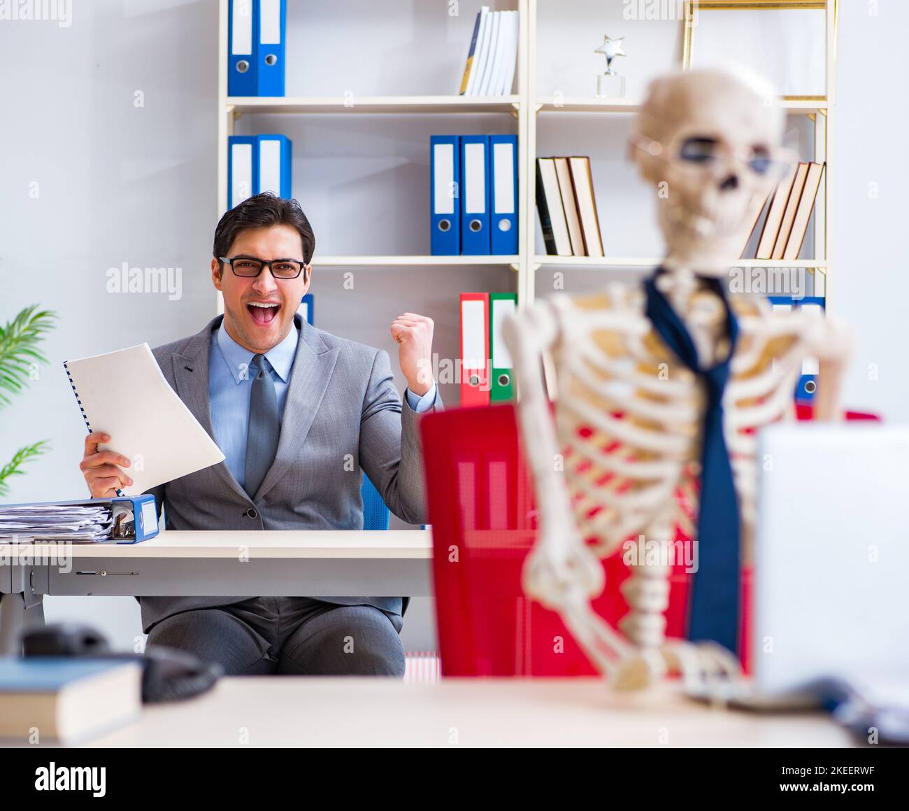 The businessman working with skeleton in office Stock Photo - Alamy