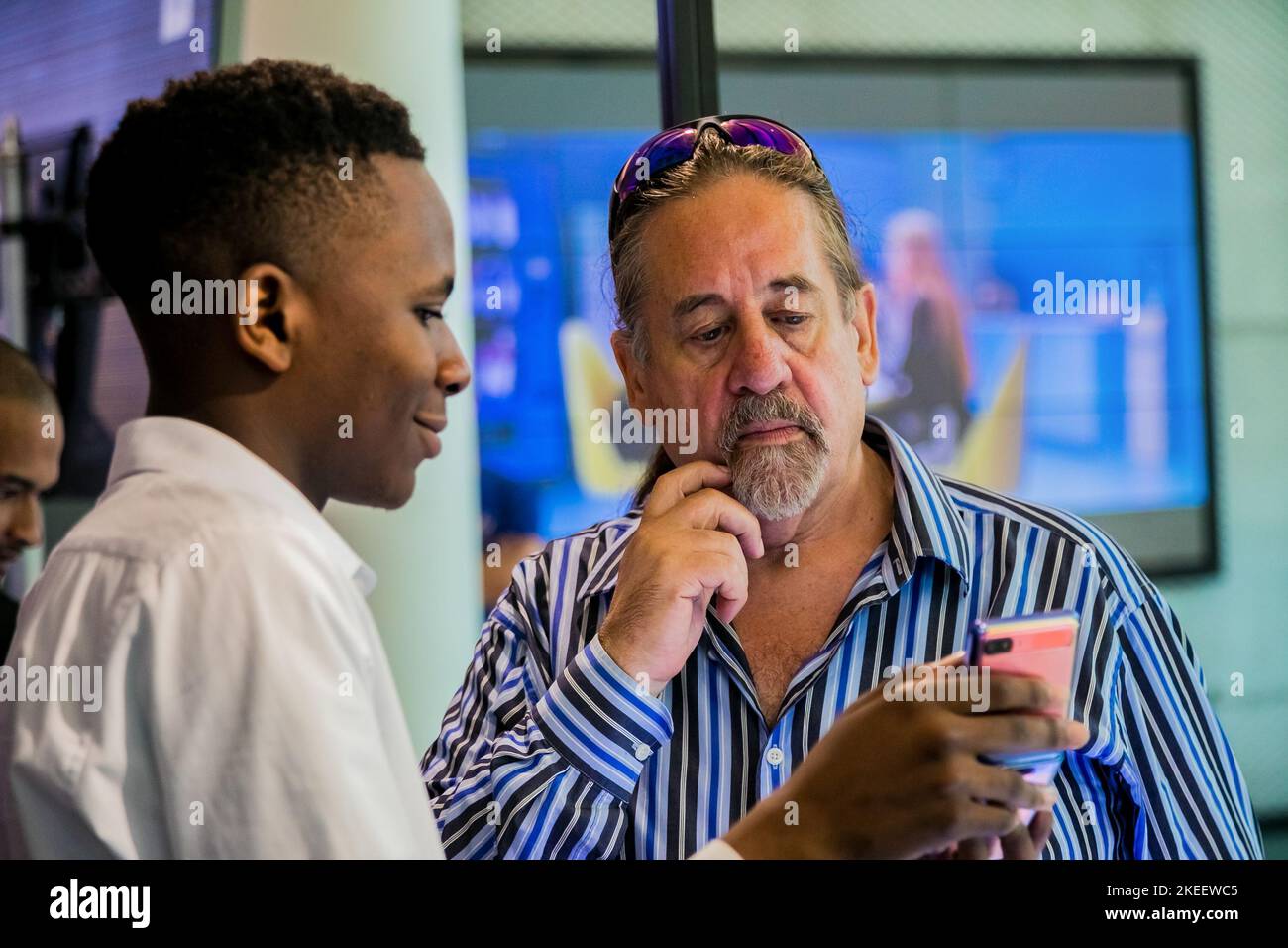 A black worker presenting a new Samsung phone to a white customer at a ...