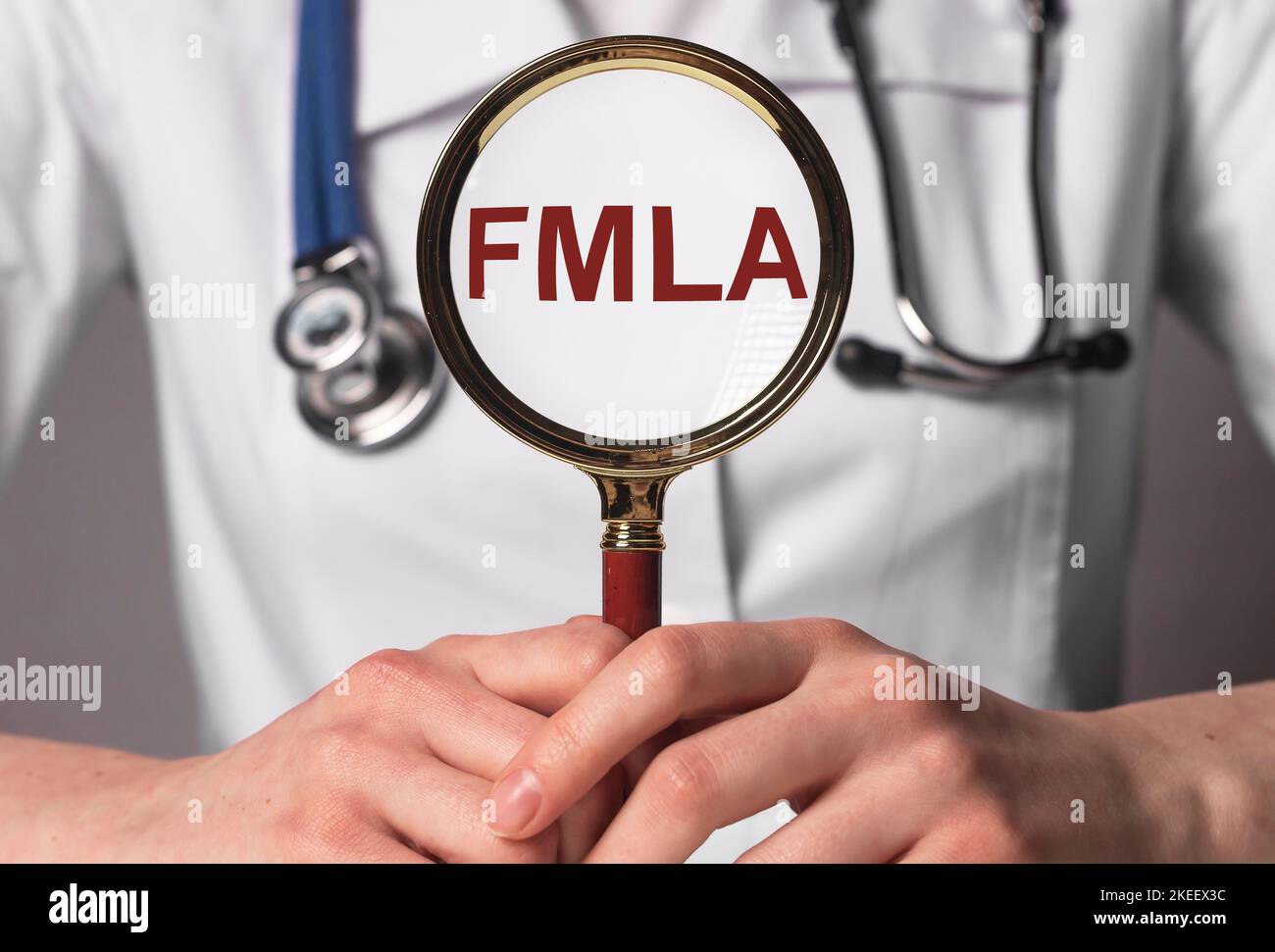 FMLA word through magnifying glass in doctors hand Stock Photo - Alamy