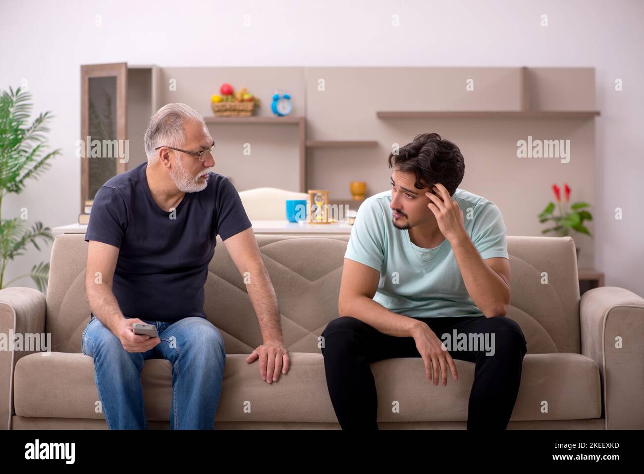 Old father and young son watching tv during pandemic Stock Photo - Alamy