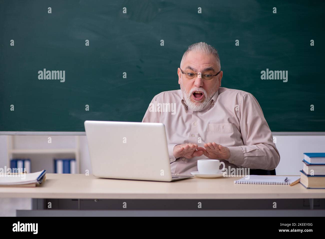 Old teacher drinking coffee in the classroom Stock Photo - Alamy