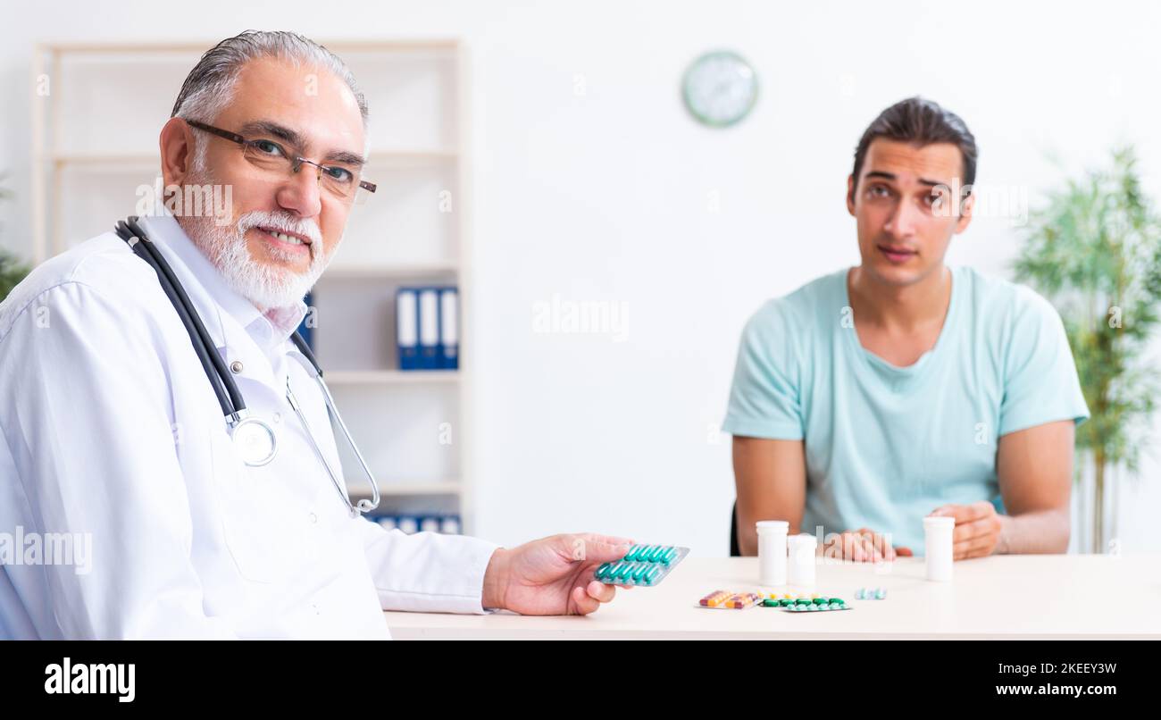 The young man visiting old male doctor Stock Photo - Alamy