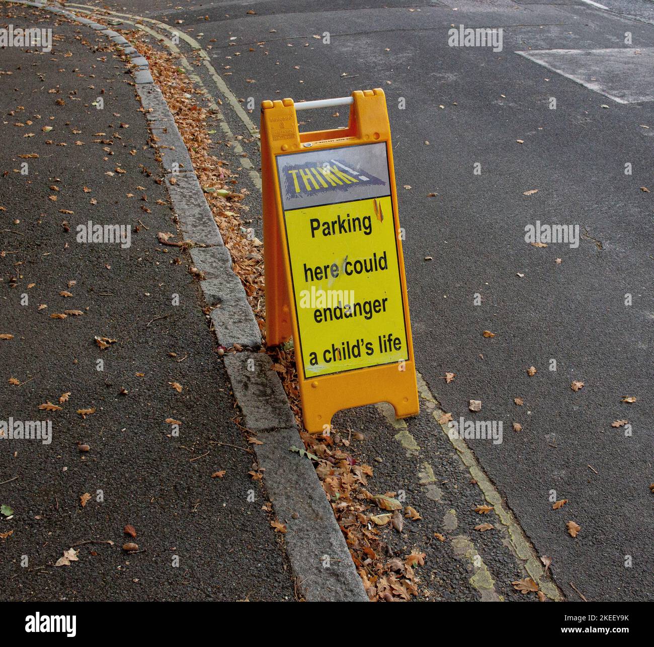 Plastic sign on road warning drivers: "Parking here could endanger a ...