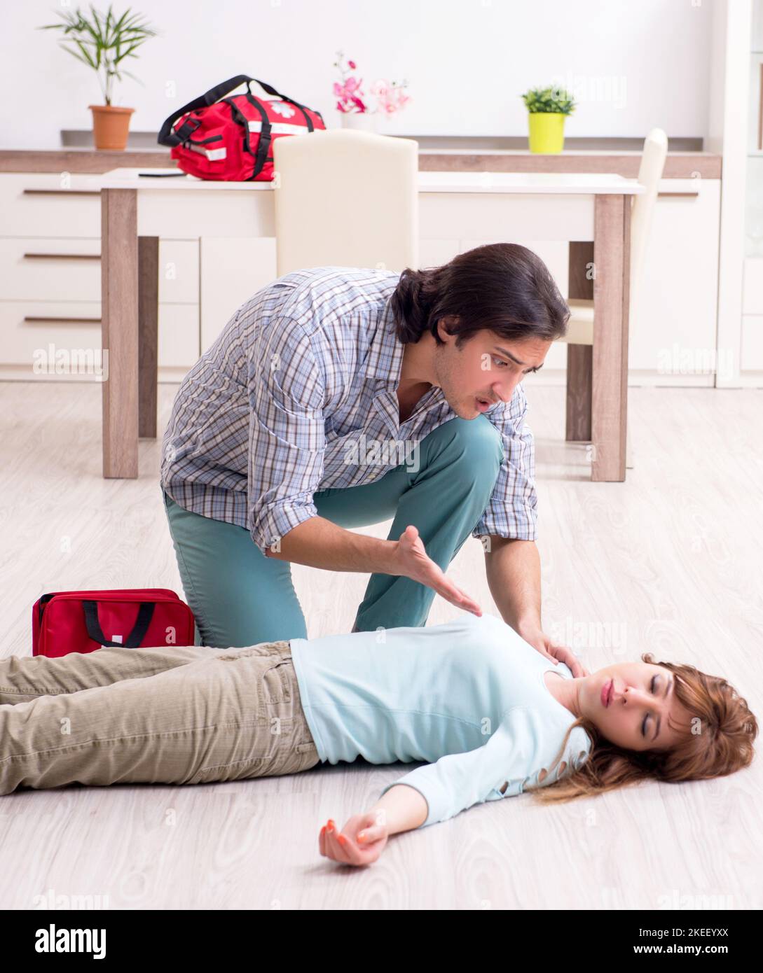 The young couple in first aid concept at home Stock Photo - Alamy