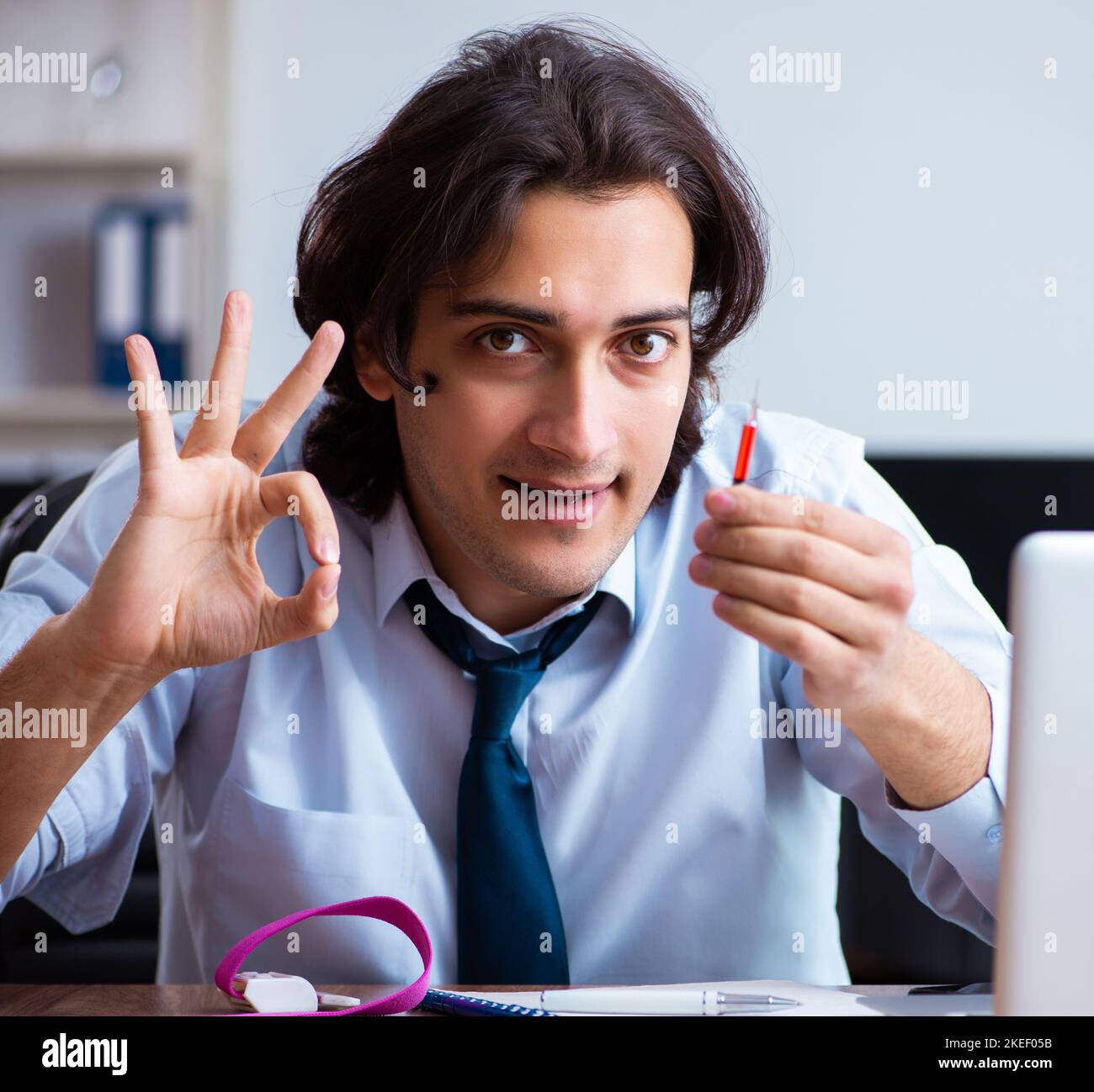 The young man having problems with narcotics at workplace Stock Photo ...