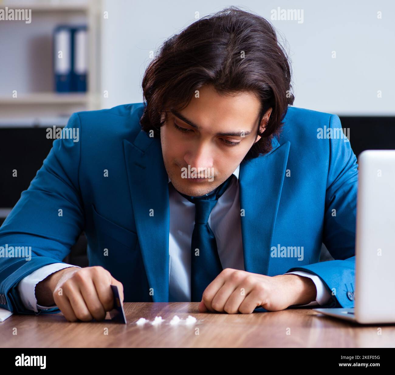 The young man having problems with narcotics at workplace Stock Photo ...