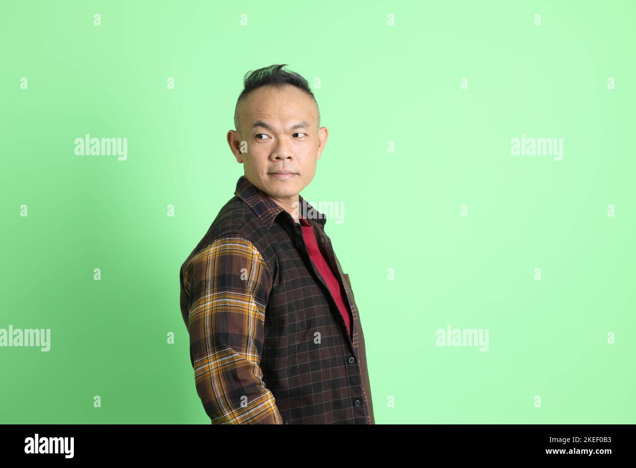 The 40s adult Asian man with plaid shirt standing on the green ...