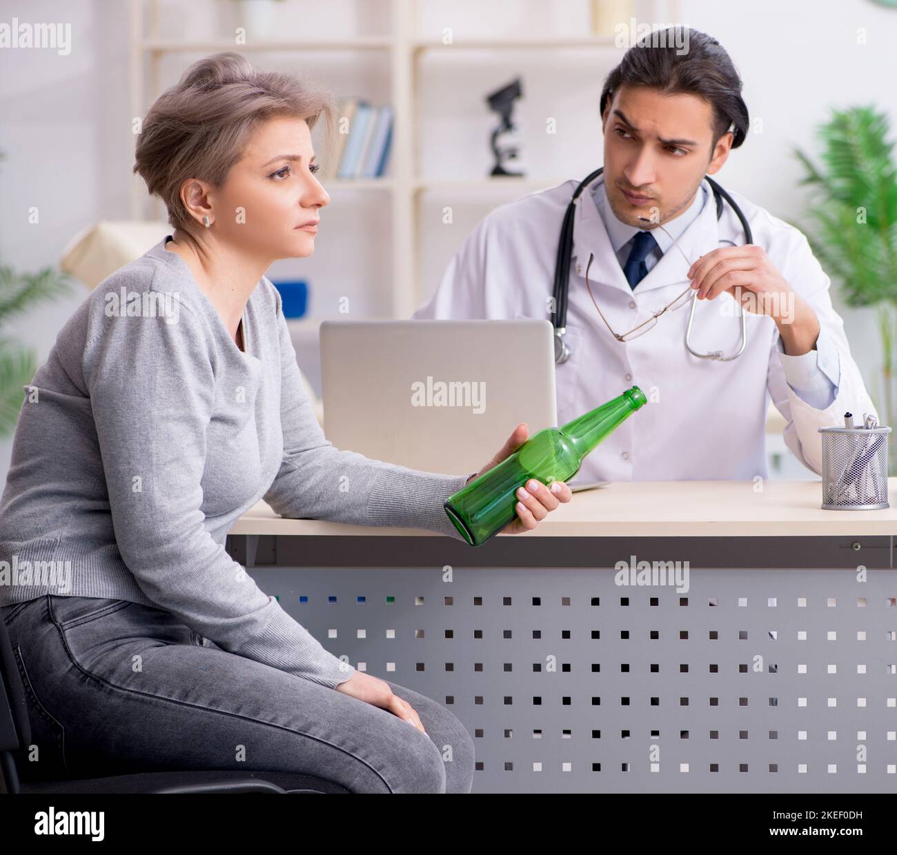 The female alcoholic visiting young male doctor Stock Photo - Alamy