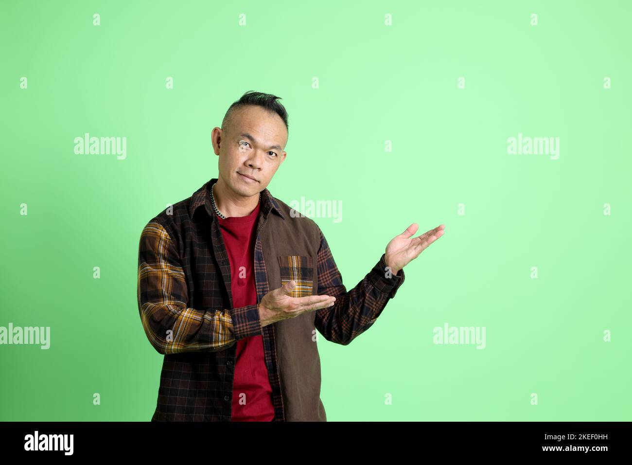 The 40s adult Asian man with plaid shirt standing on the green ...