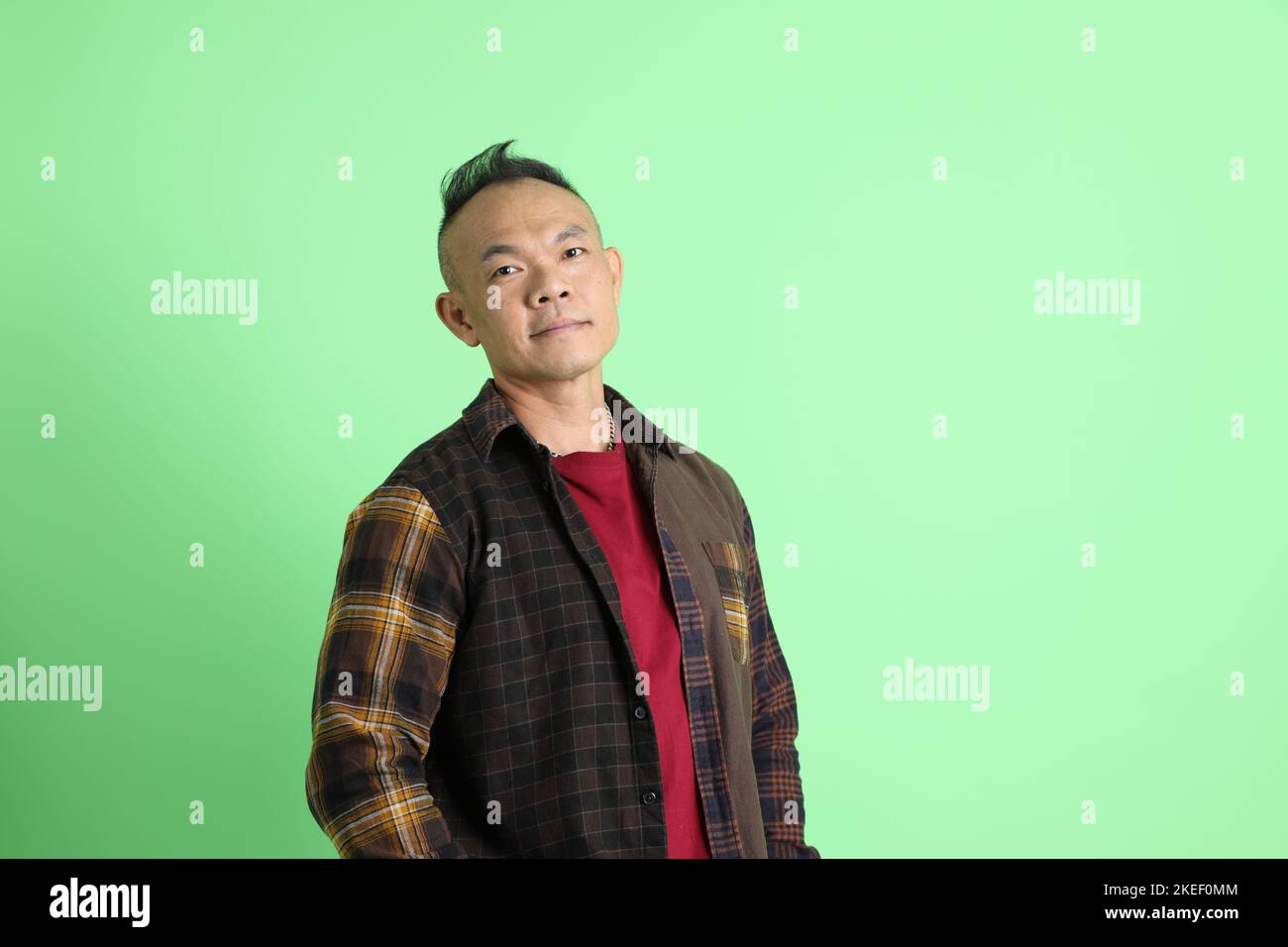 The 40s adult Asian man with plaid shirt standing on the green ...