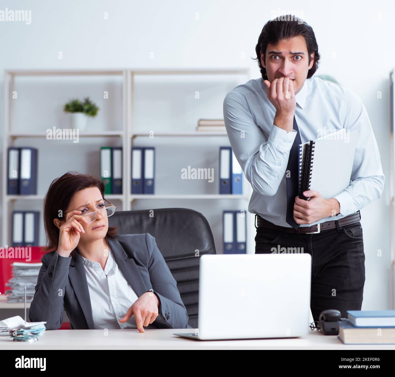 The old female boss and young male employee in the office Stock Photo ...