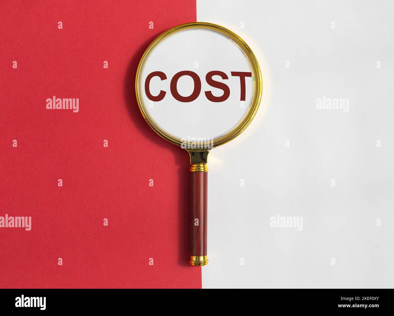 Word cost through magnifying glass on red and white background with ...