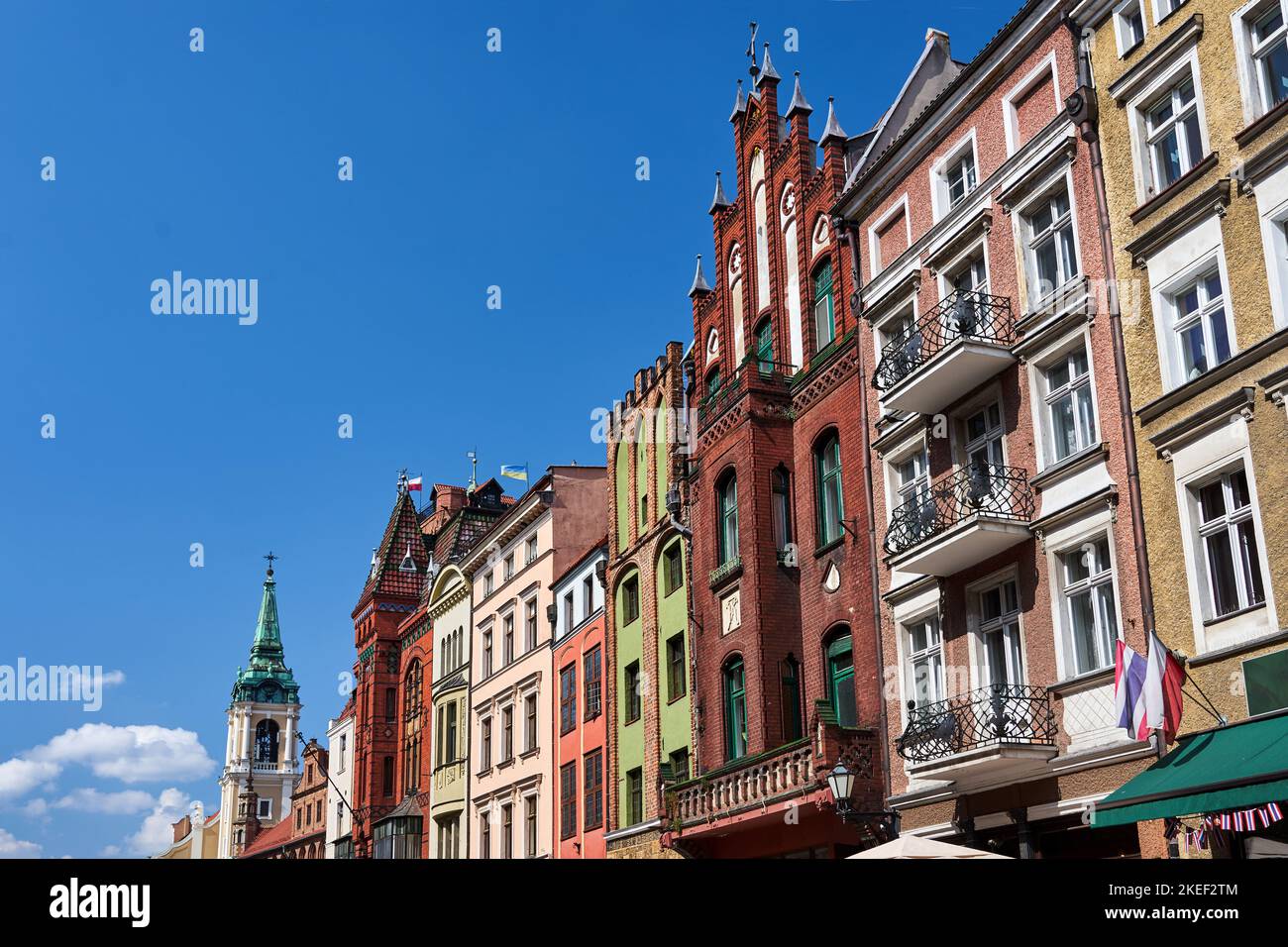 The belfry of a church and facades of historic tenement houses in Torun ...