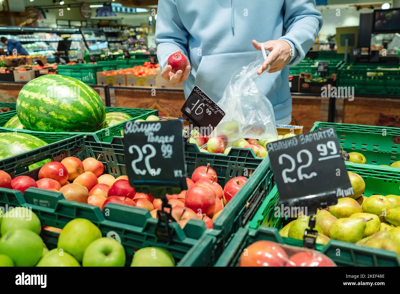 A man buys food, . A male customer chooses apples, taking products from ...