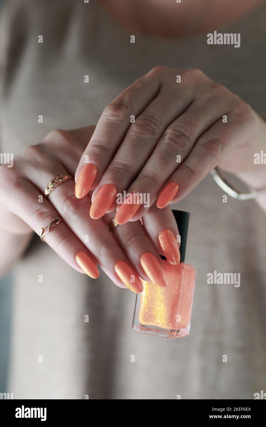 Female hand with long nails and a yellow orange nail polish Stock Photo ...