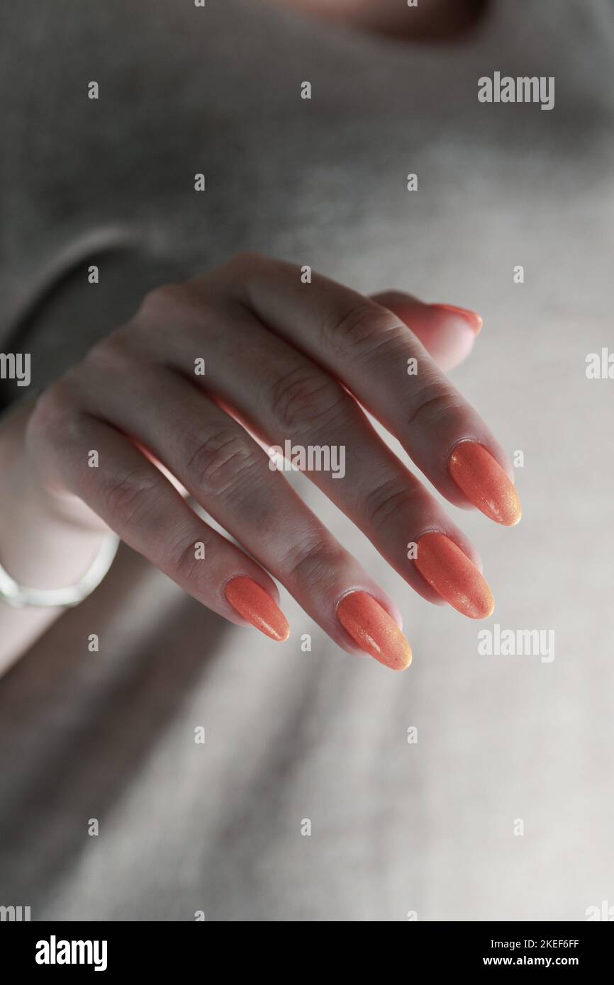 Female hand with long nails and a yellow orange nail polish Stock Photo ...