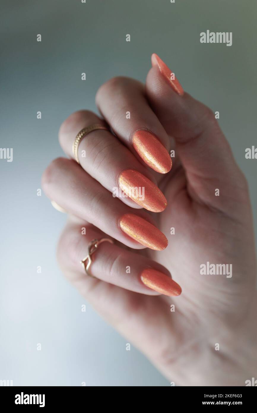 Female hand with long nails and a yellow orange nail polish Stock Photo ...