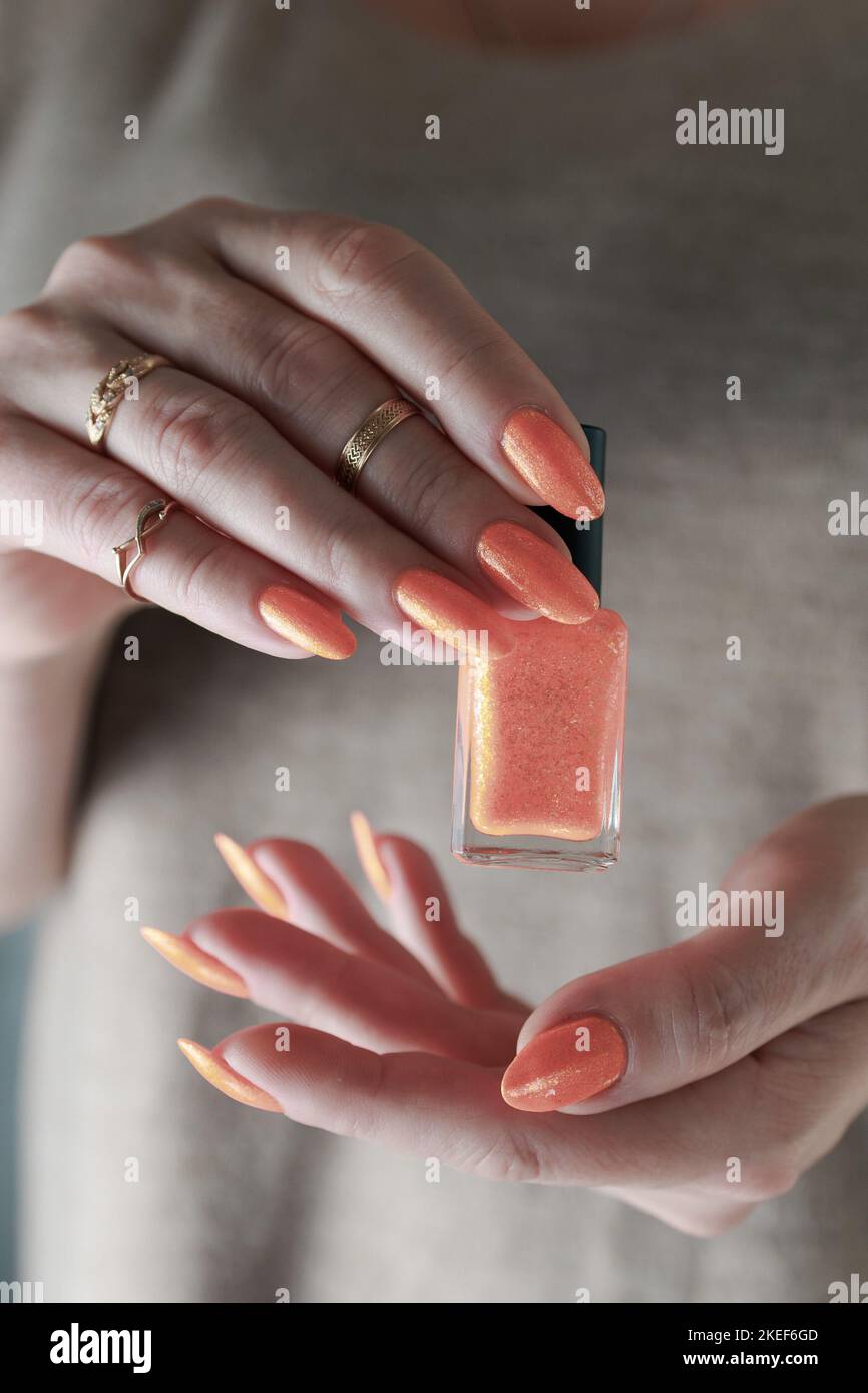 Female hand with long nails and a yellow orange nail polish Stock Photo ...