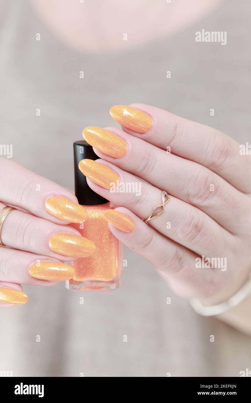 Female hand with long nails and a yellow orange nail polish Stock Photo ...