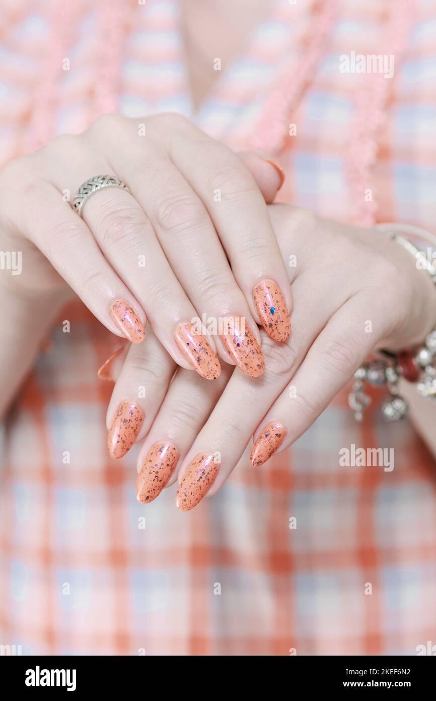 Woman's hands with long nails and a bottle of orange nail polish Stock ...