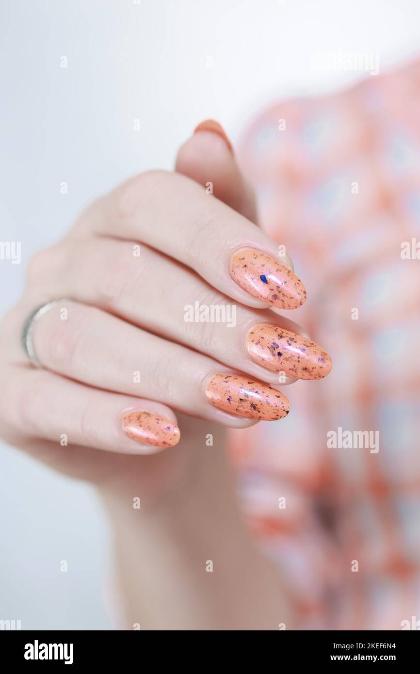 Woman's hands with long nails and a bottle of orange nail polish Stock ...
