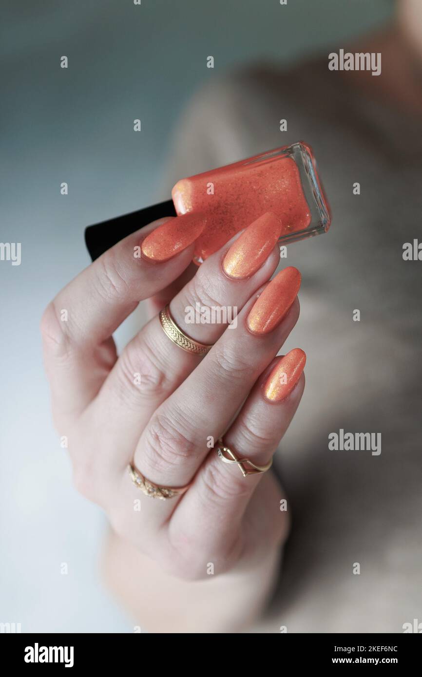 Woman's hands with long nails and a bottle of orange nail polish Stock ...