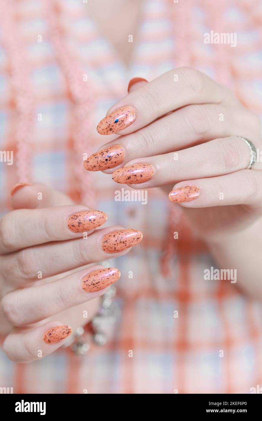 Woman's hands with long nails and a bottle of orange nail polish Stock ...