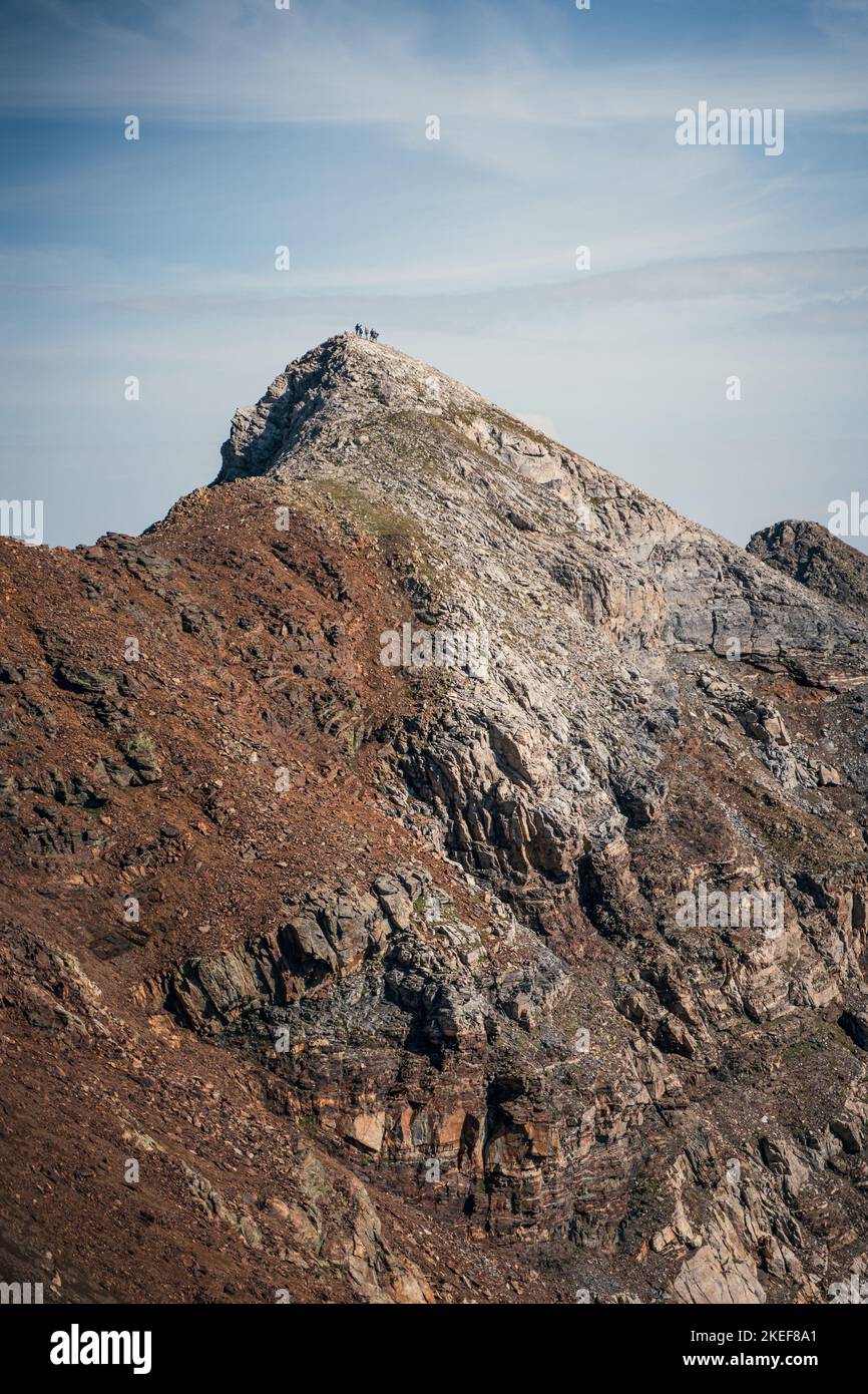 A vertical of a rugged, rocky mountain top captured against the sky ...