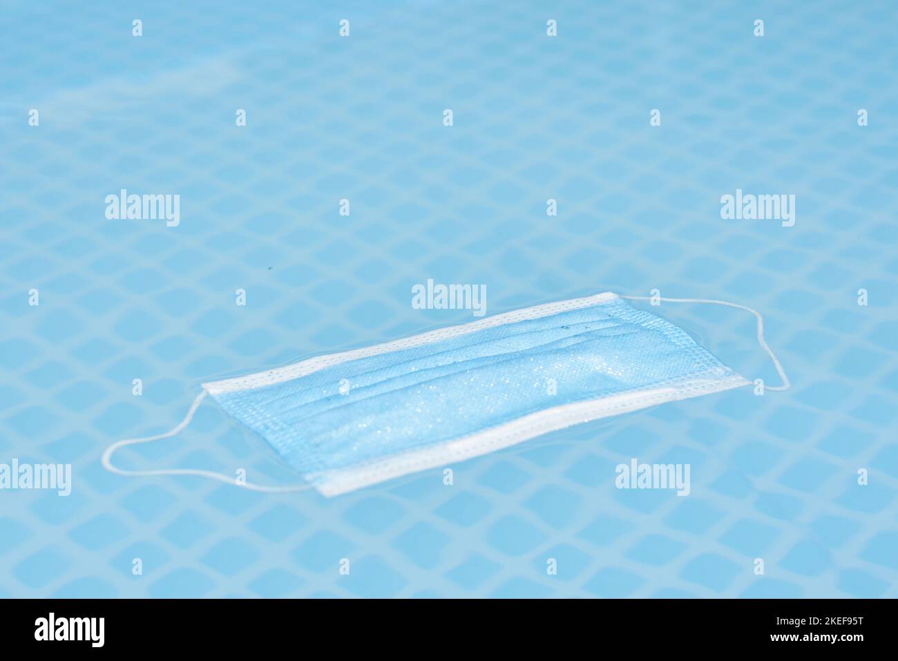 a face mask floating in a swimming pool, with water droplets on the ...