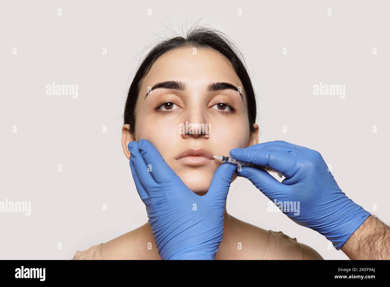 a woman getting an injection on her face from a plastic surgeon's hand ...