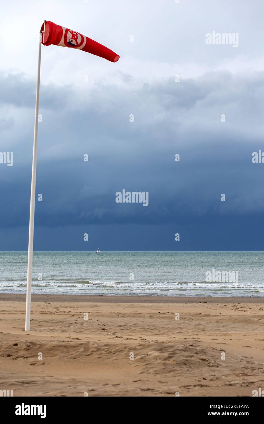 Red and white windsock indicator on blue sky with many white clouds ...