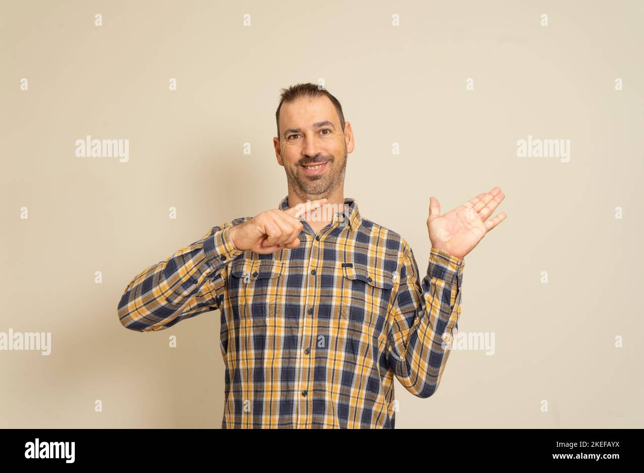 Portrait Of Positive Bearded Latin Man Wearing A Plaid Shirt Isolated Over Beige Background