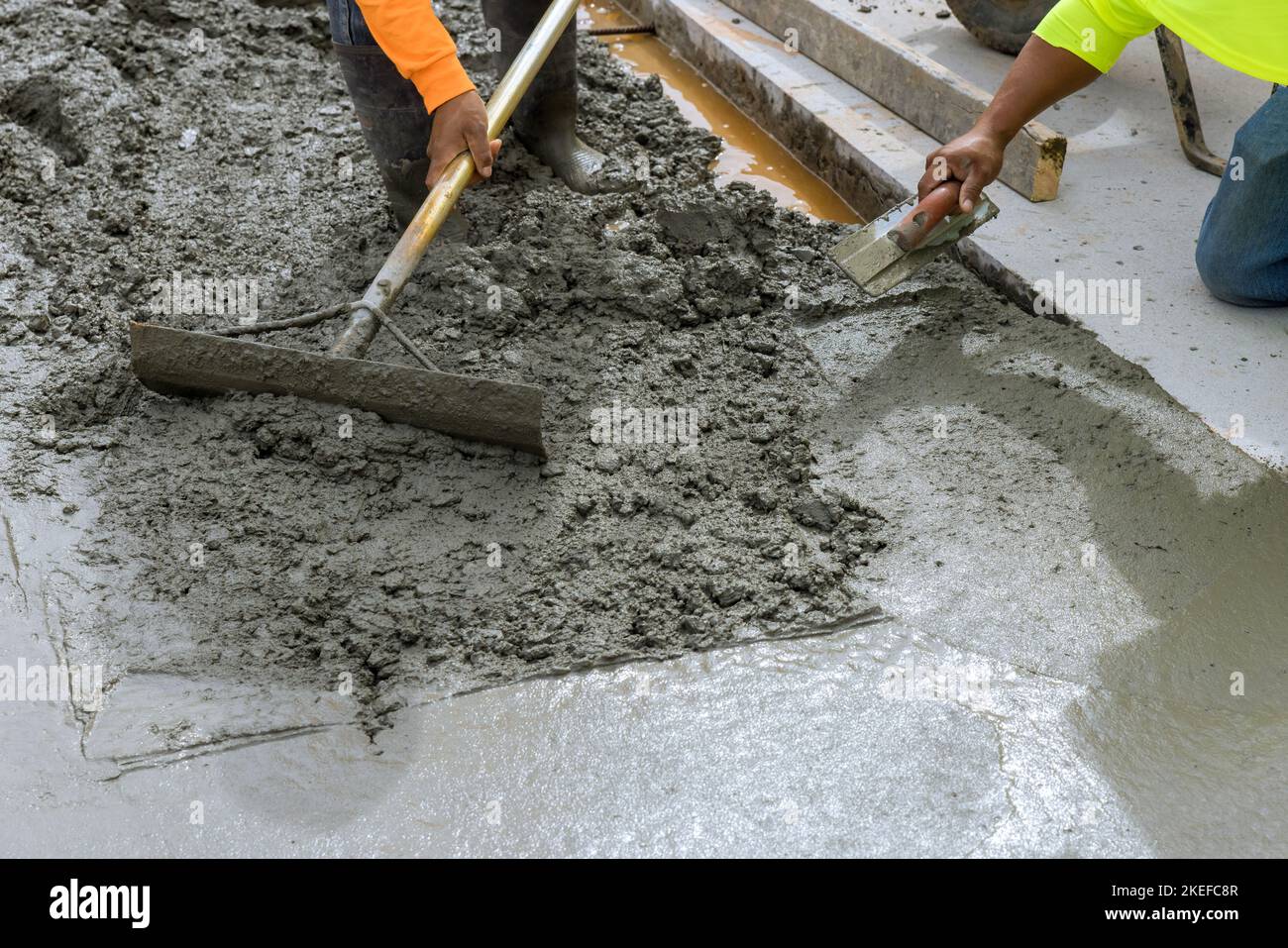 Construction worker pouring cement to create new sidewalk on side of ...