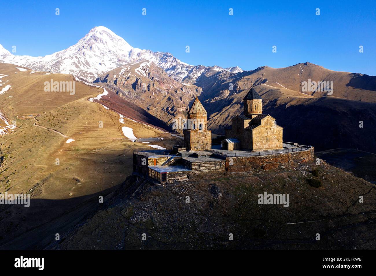 Aerial view of Gergeti Trinity Church in spring morning light with snow ...