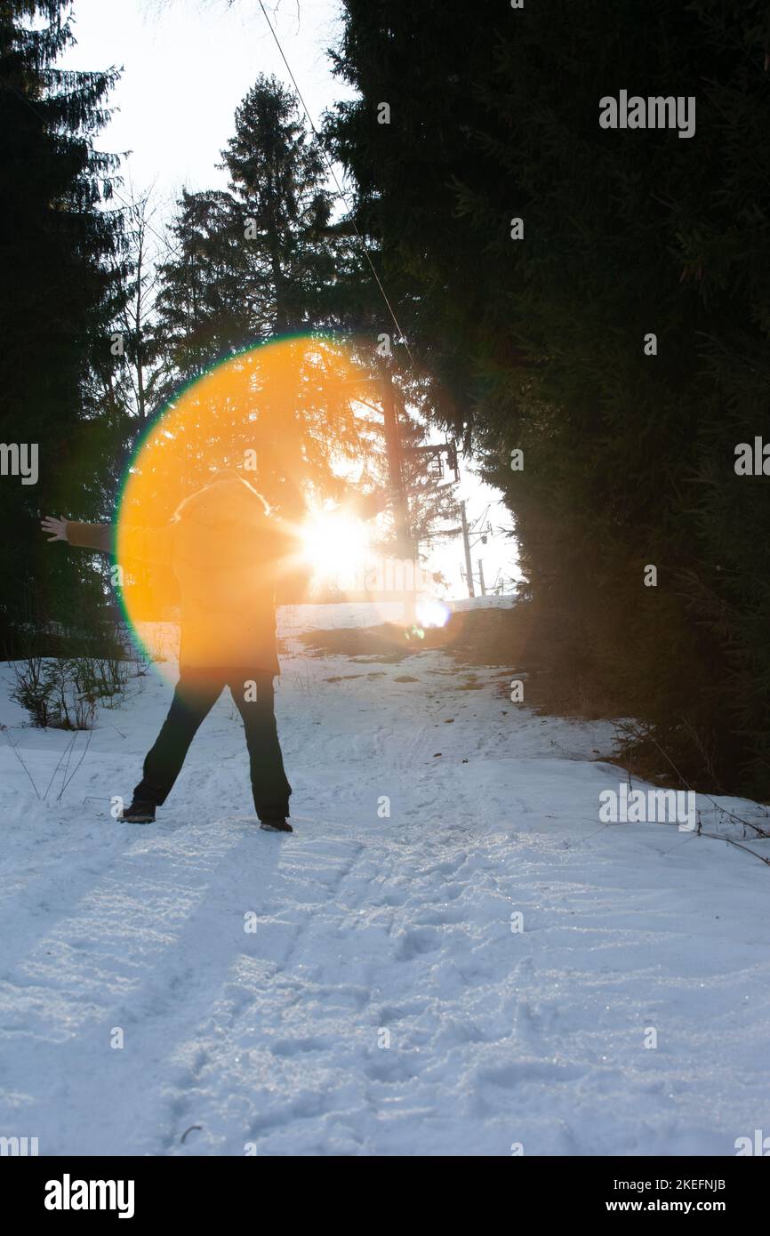 A person is in the sunlight, from a low angle. The forest frames the ...