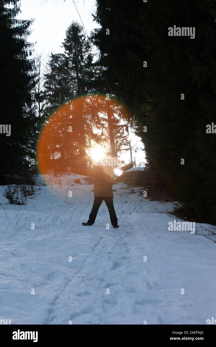 A person is in the sunlight, from a low angle. The forest frames the ...