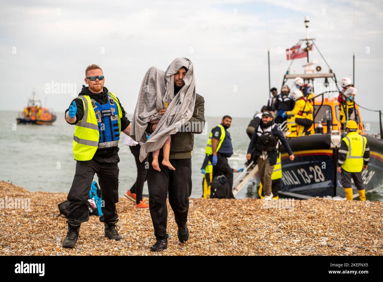 A young Migrant man with a small child arriving on the Beach at ...