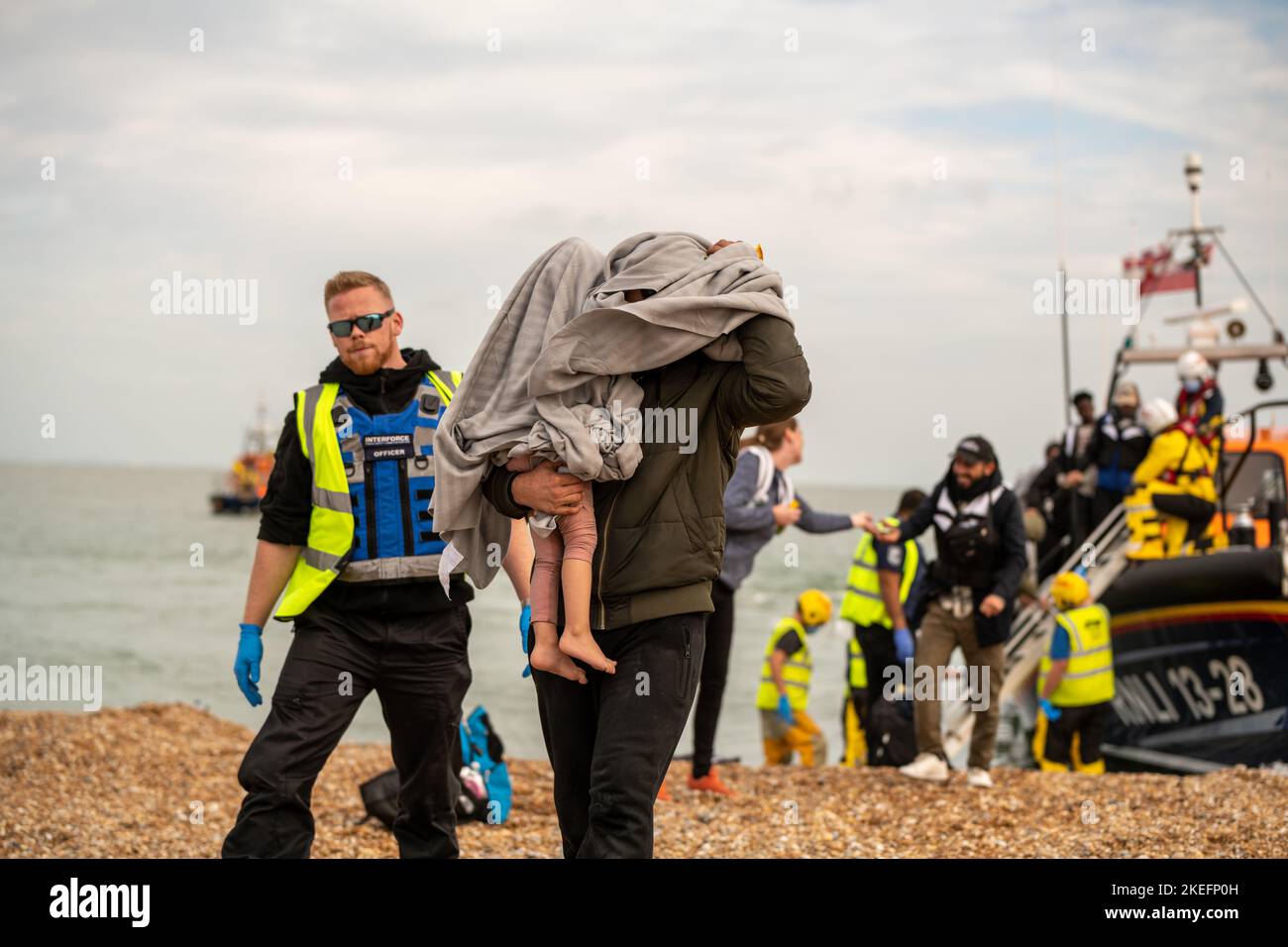 A young Migrant man with a small child arriving on the Beach at ...