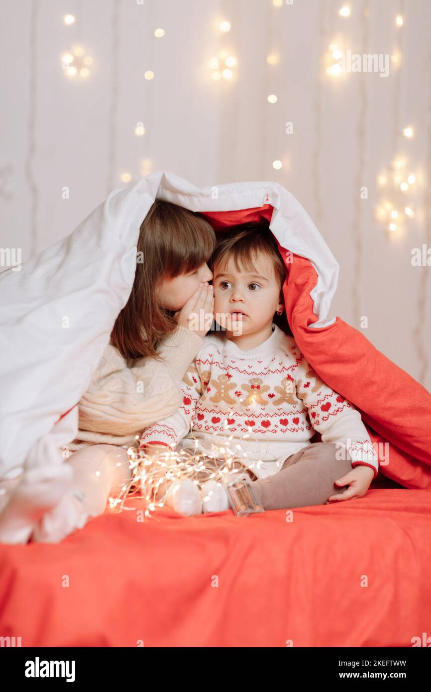 Two charming little girls in worm clothes with winter ornaments are ...