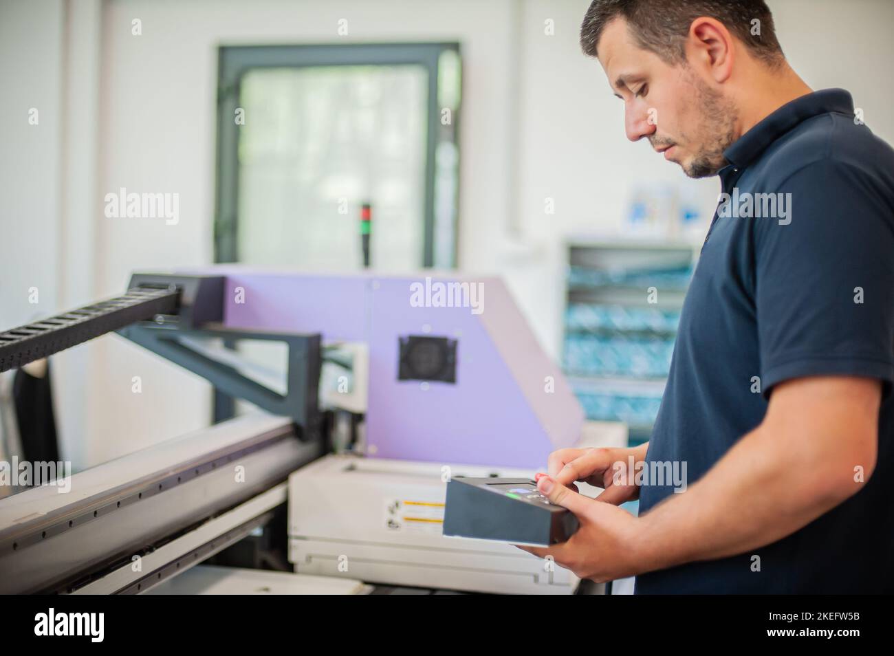 In the printing house, an experienced technician works on a UV printer ...