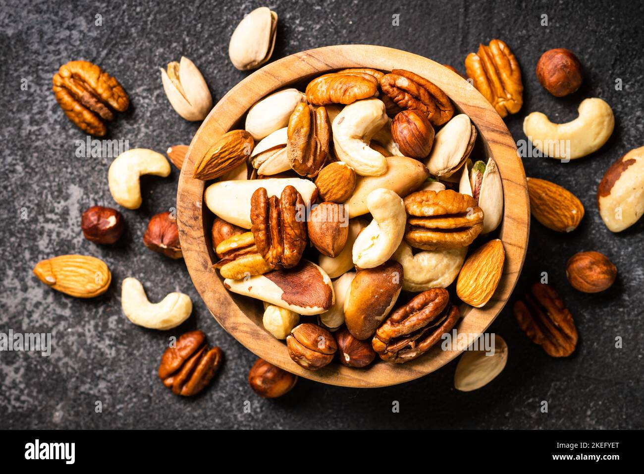 Assortment of nuts in wooden bowl on dark stone table. Cashew ...