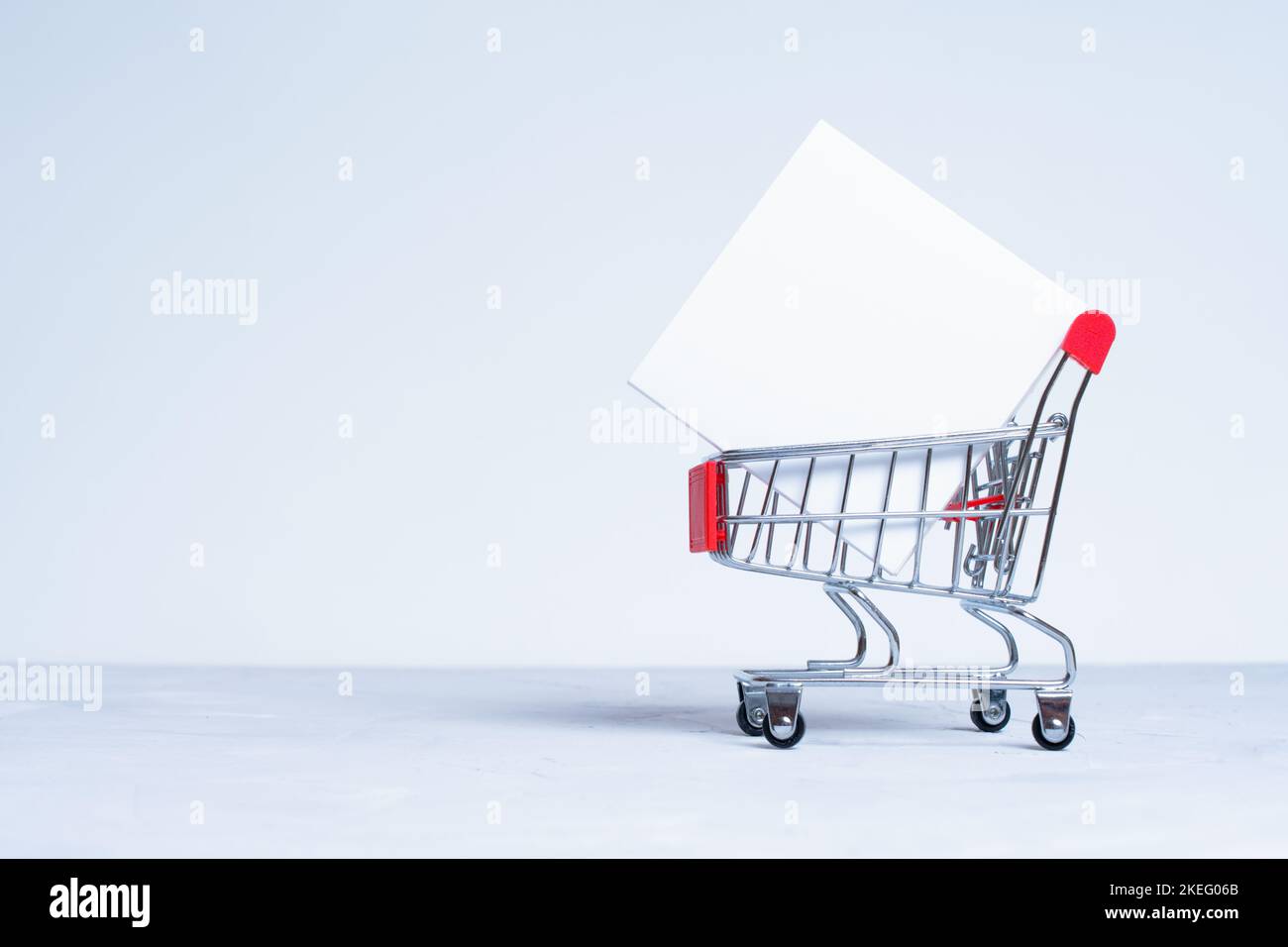 Small white shipping box in a miniature shopping trolley isolated on ...