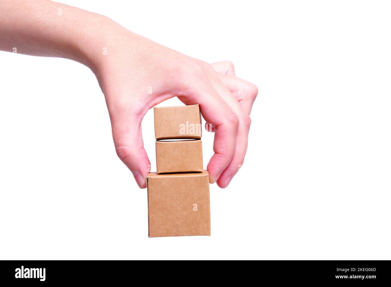 Hand pinch holding a bunch of tiny brown paper shipping boxes isolated ...