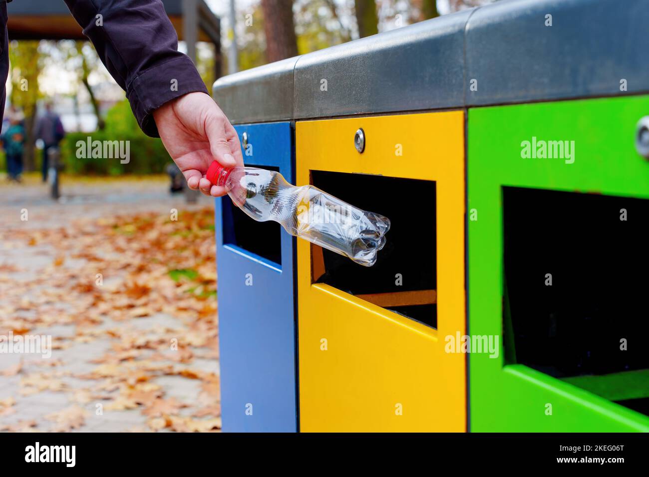Throwing a plastic bottle into a color-coded waste collection bin ...