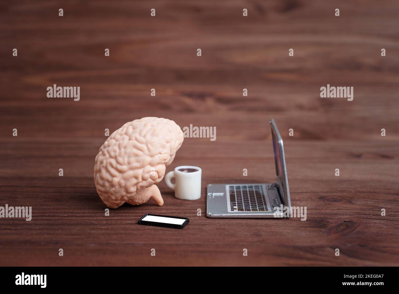 Human brain figurine placed on a wooden table with toy laptop ...
