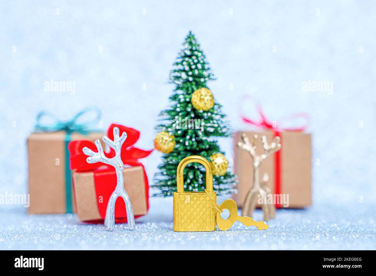 Tiny padlock and key placed in front of a miniature toy Christmas tree ...
