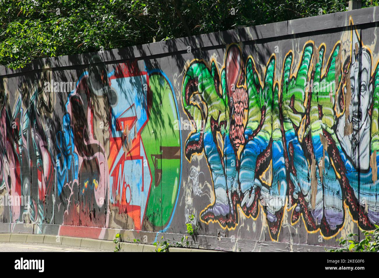 A vandalised wooden fence full of colourful graffiti in an urban ghetto ...
